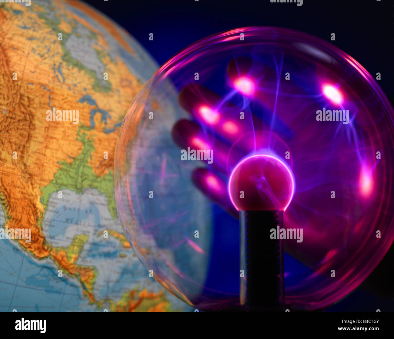 Plasma ball touched by a hand with an illuminated globe in the ...