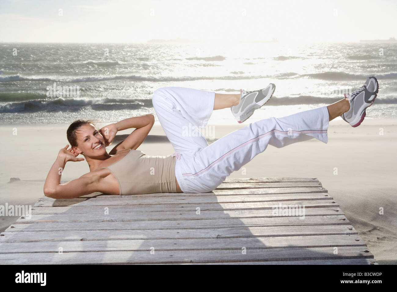 Young woman doing Sit-Ups on beach Stock Photo - Alamy
