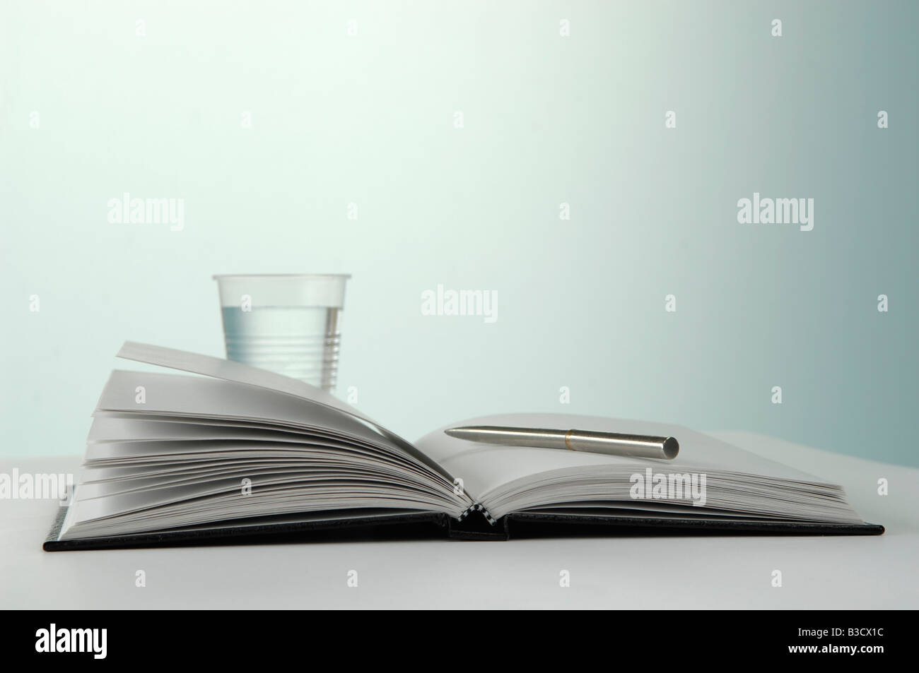 Glass of water with pen and notebook Stock Photo - Alamy