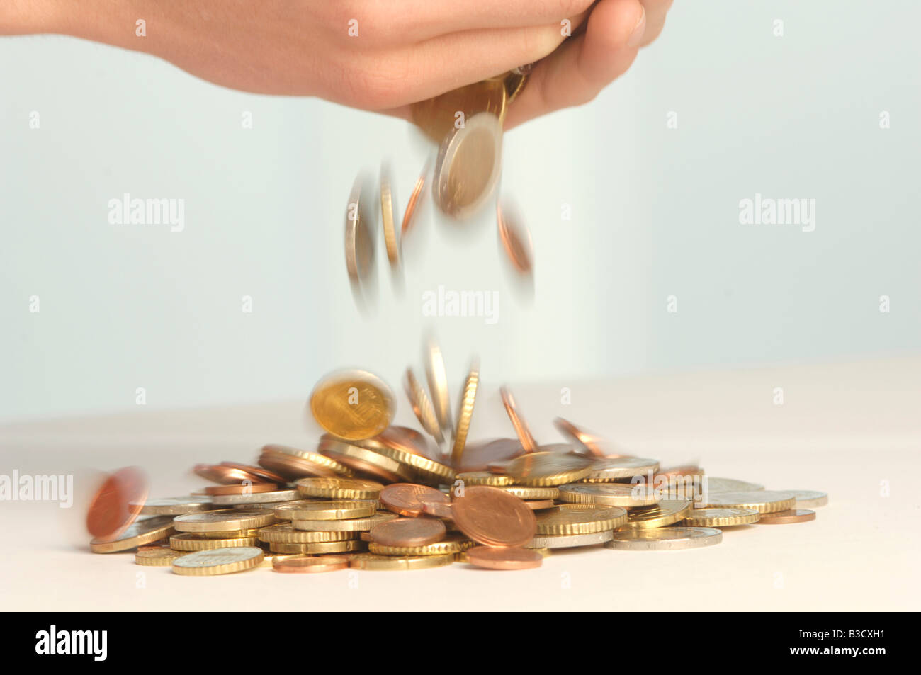 Coins falling from hands Stock Photo - Alamy