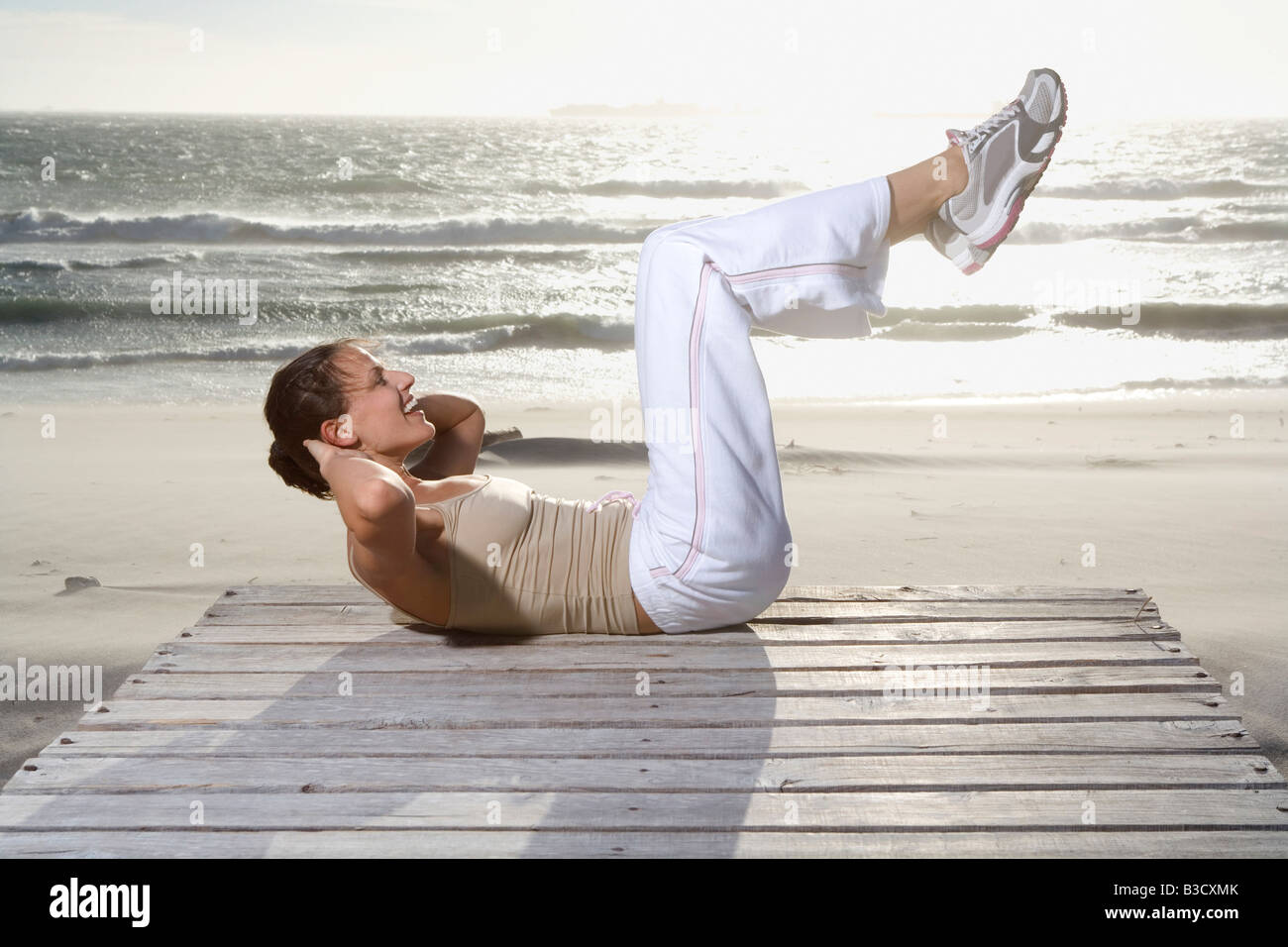 Young woman doing Sit-Ups on beach Stock Photo - Alamy