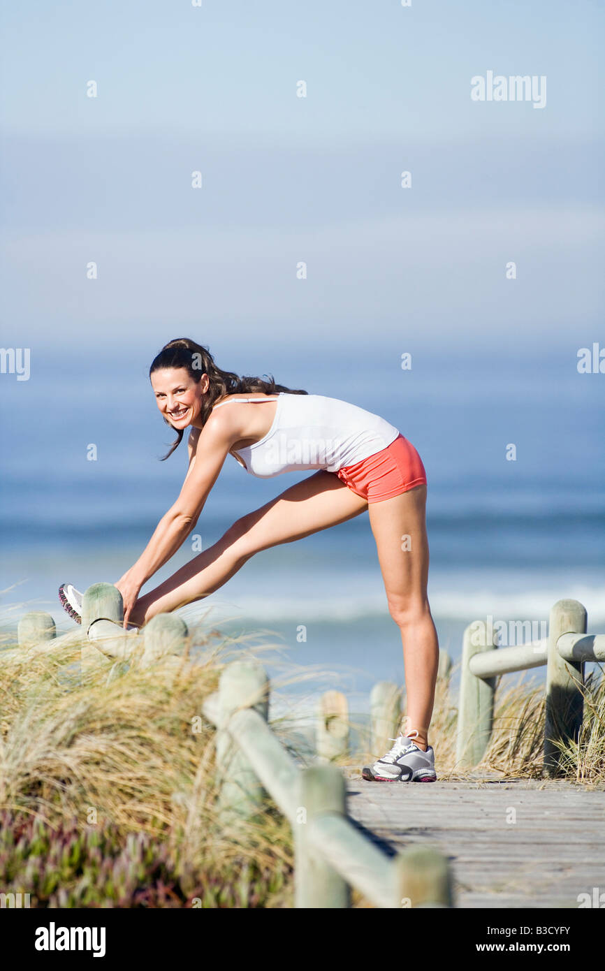 South Africa, Young woman stretching leg by fence Stock Photo - Alamy