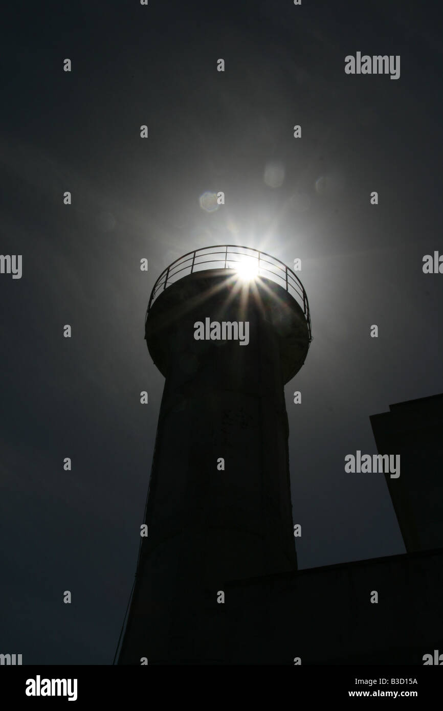 one lit lighthouse on rocks against dark sky Stock Photo - Alamy