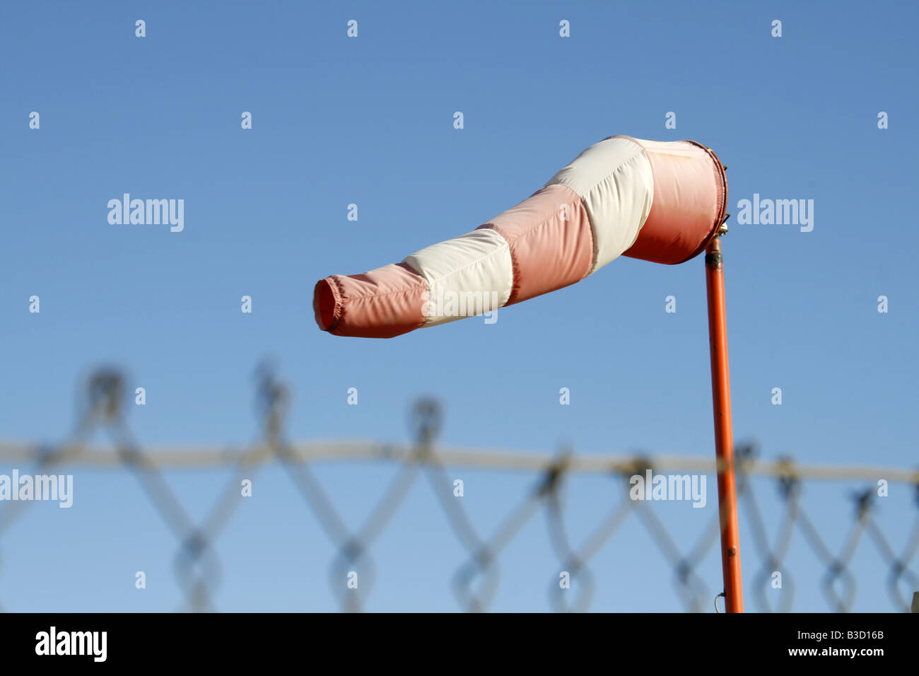 one wind sock and metal fence in wind at airport Stock Photo - Alamy