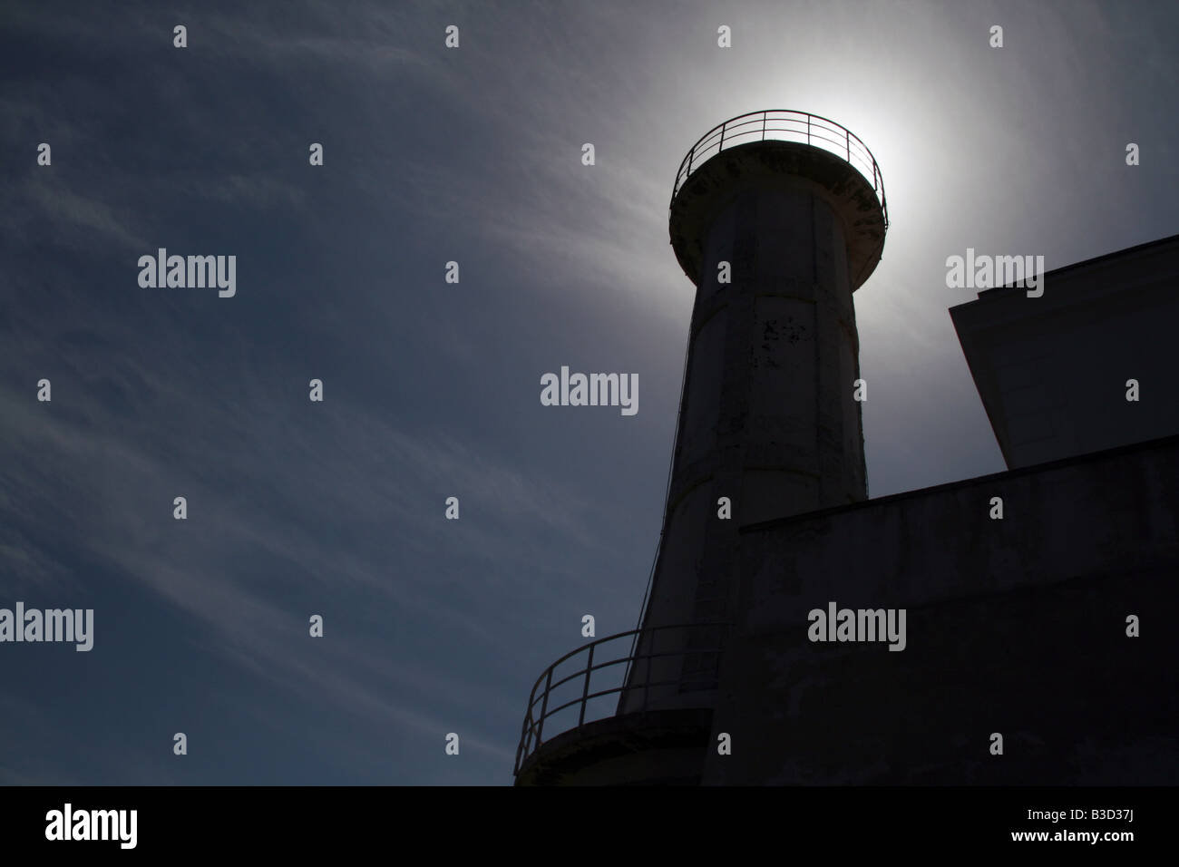 one lit lighthouse on rocks against dark sky Stock Photo - Alamy