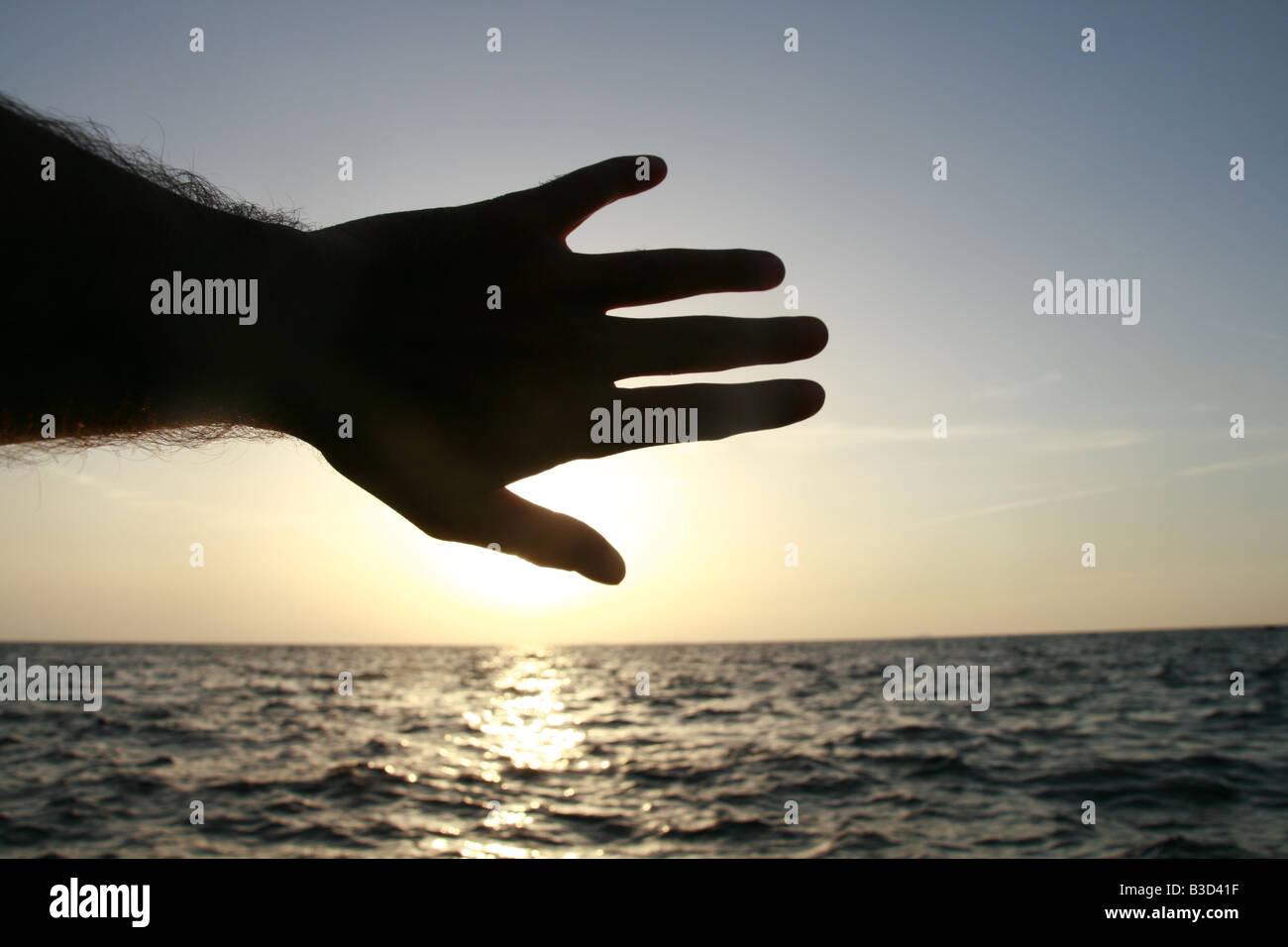 one raised hand by sea with beautiful red sunset Stock Photo - Alamy