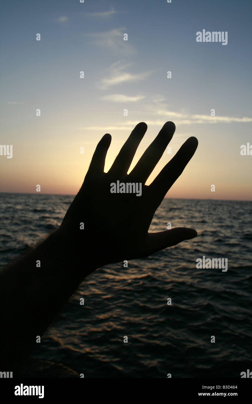 one raised hand by sea with beautiful red sunset Stock Photo - Alamy