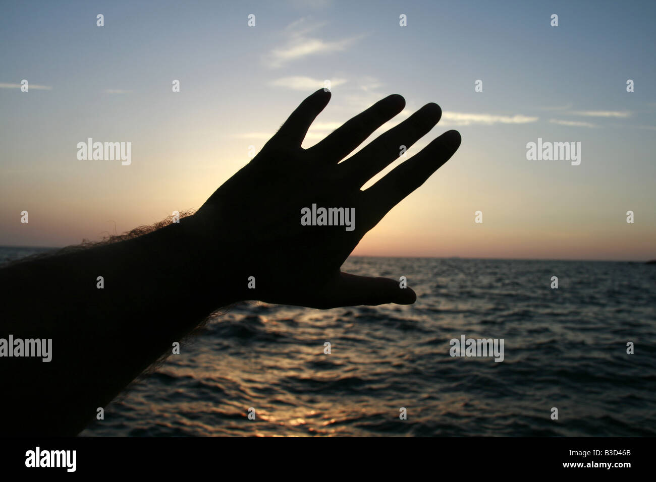 one raised hand by sea with beautiful red sunset Stock Photo - Alamy
