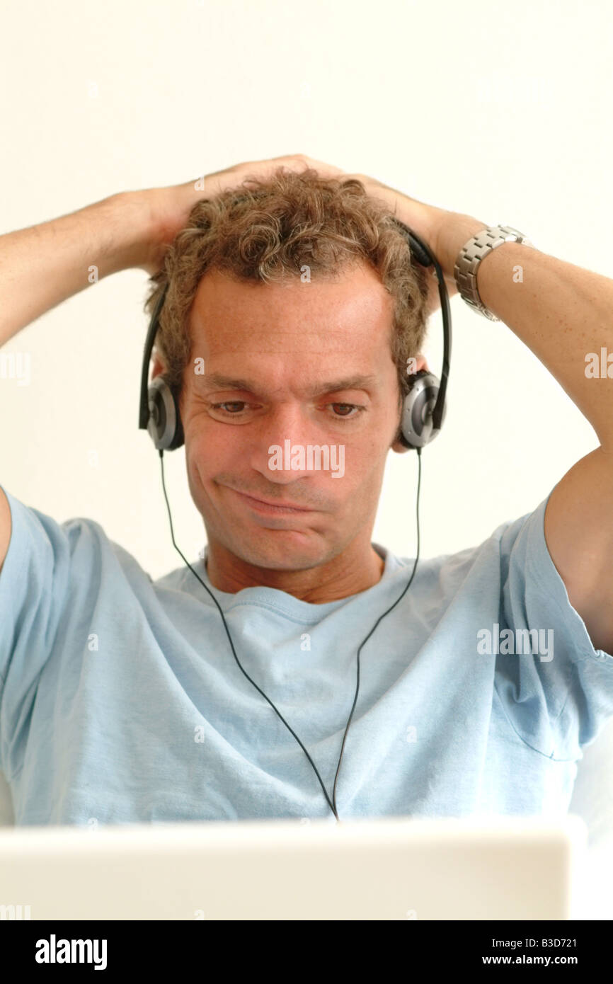 man looking at laptop computer screen with a confused expression on his ...