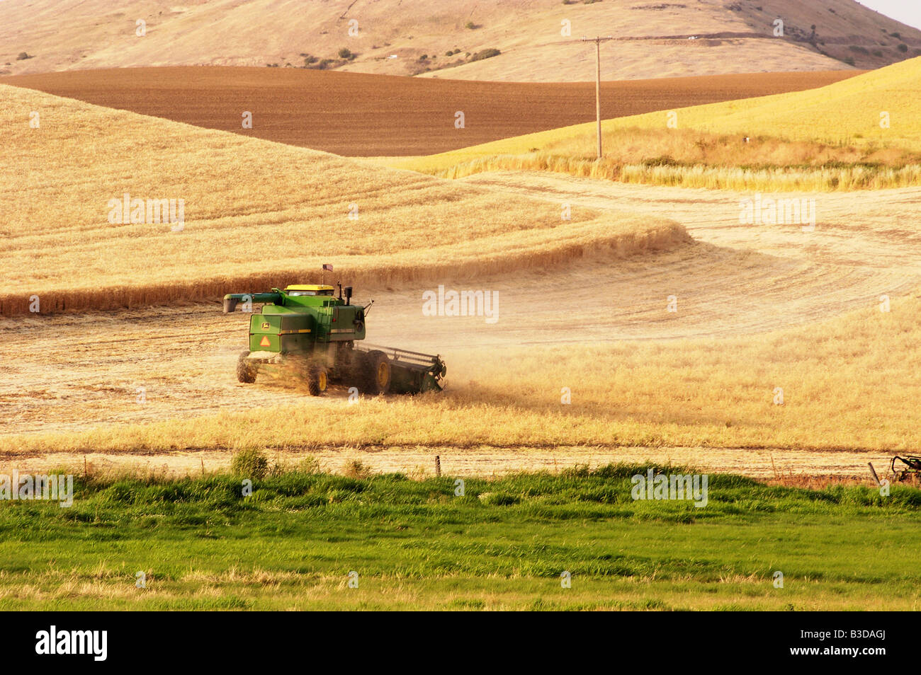 a combine harvesting the wheat crops in the rolling hills of the ...