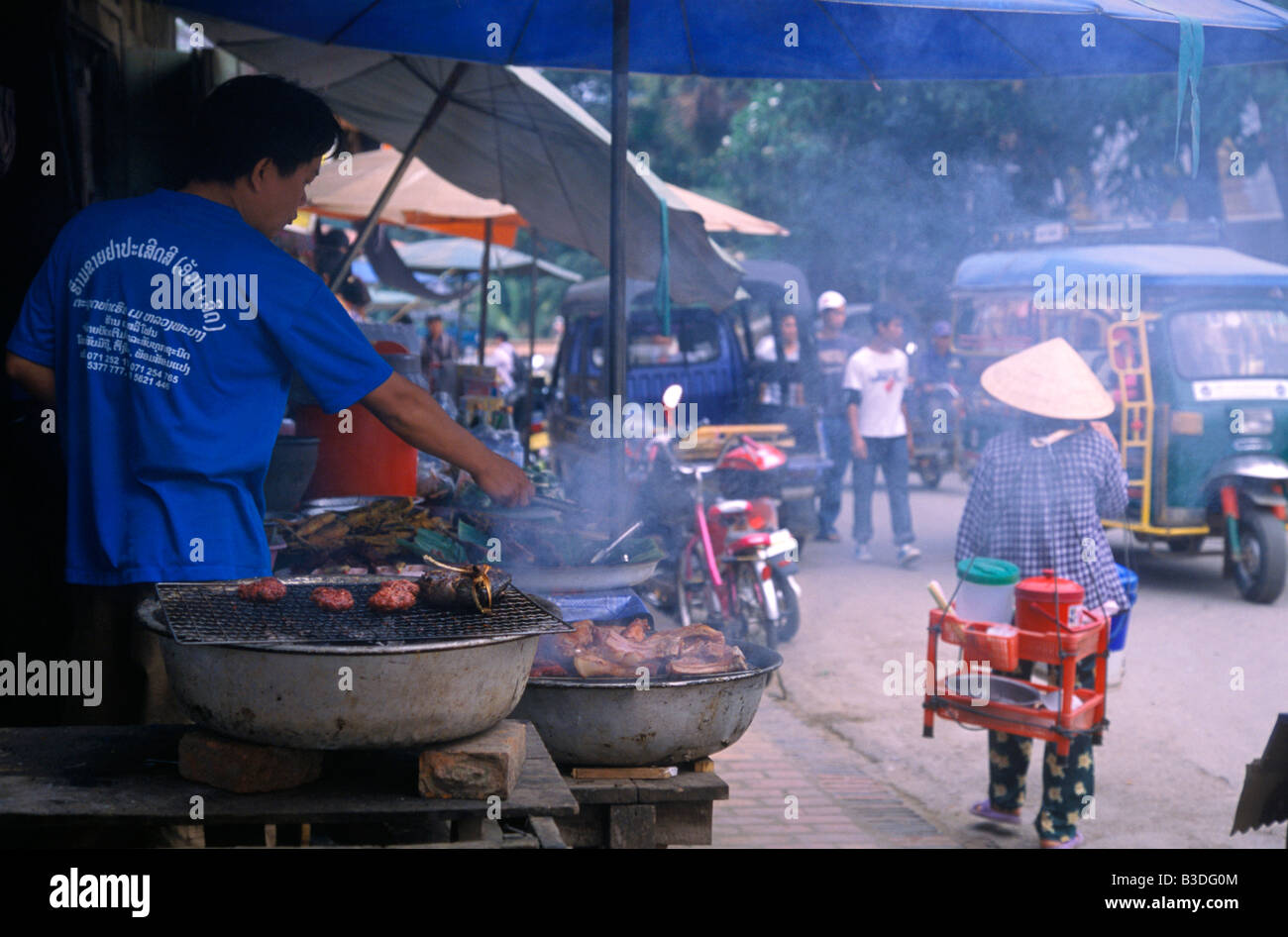 A fixed stall serving grilled meat and a woman with a moveable food ...