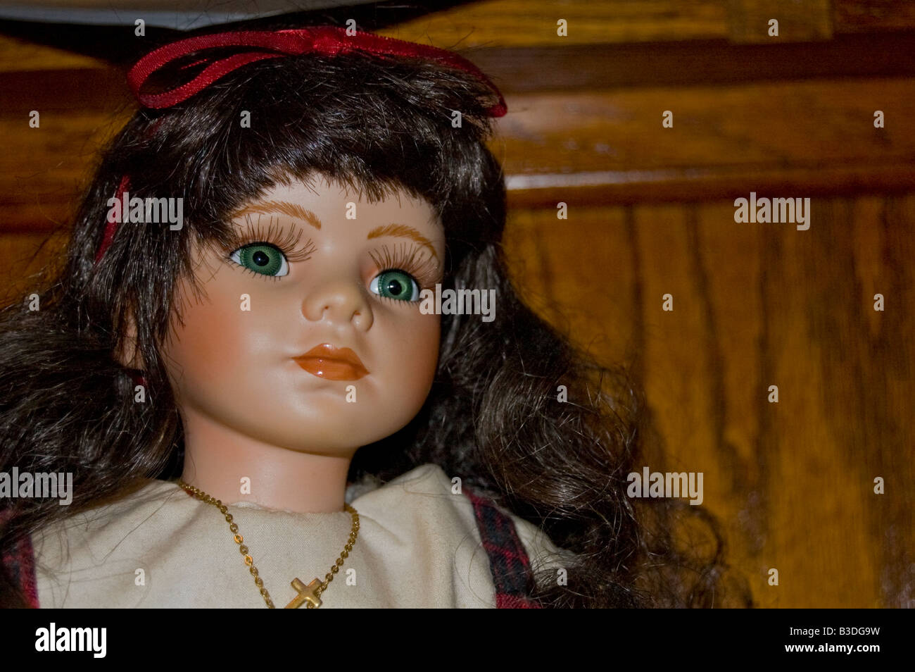 Pretty brunette female doll with a red ribbon in her hair sitting on a ...