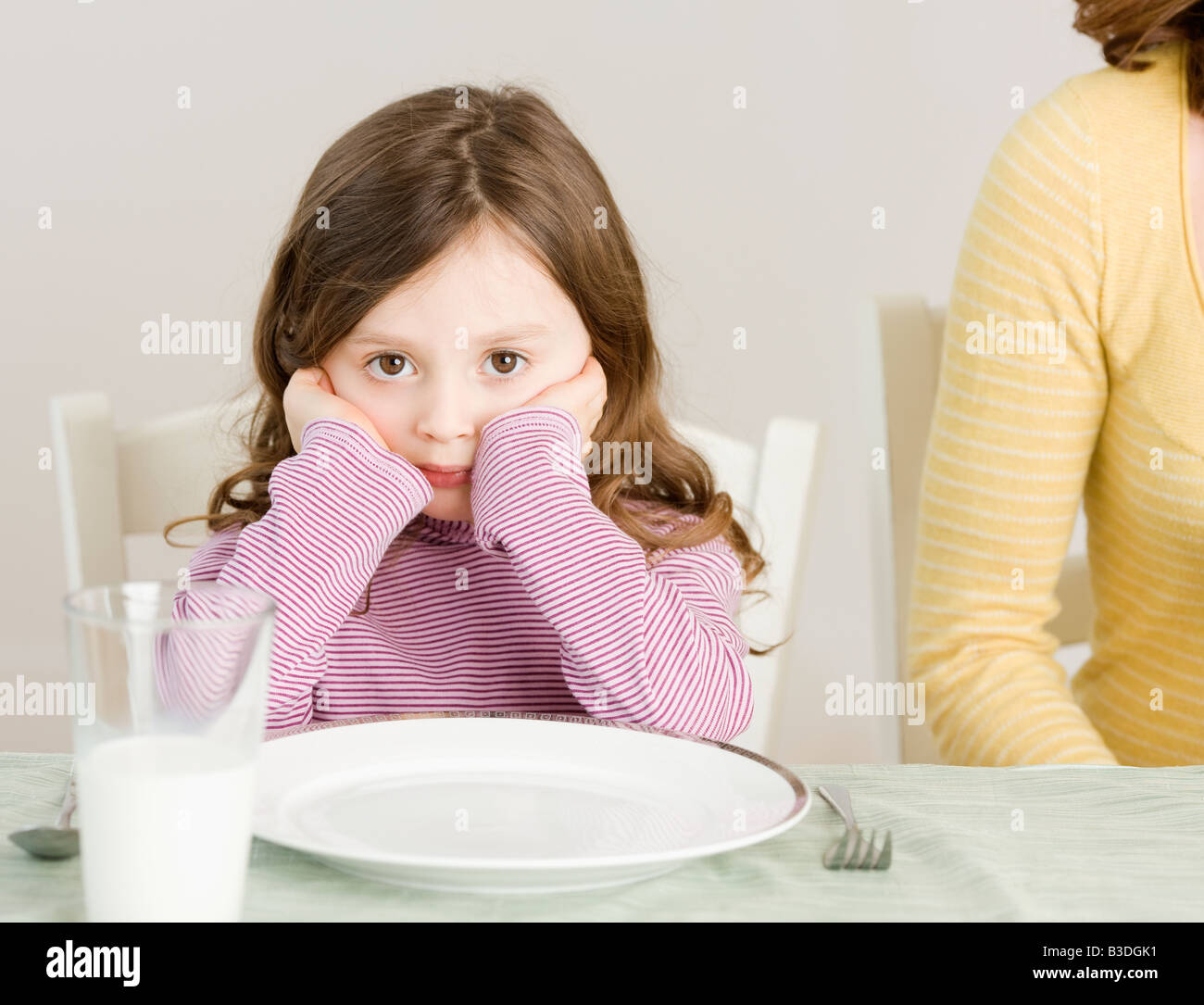 Girl sitting at dinner table Stock Photo - Alamy