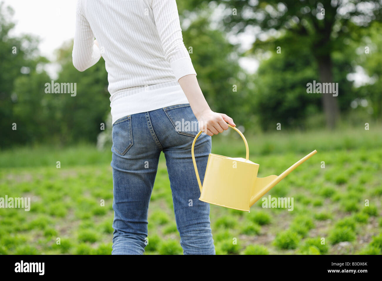 A woman holding watering can in garden Stock Photo - Alamy