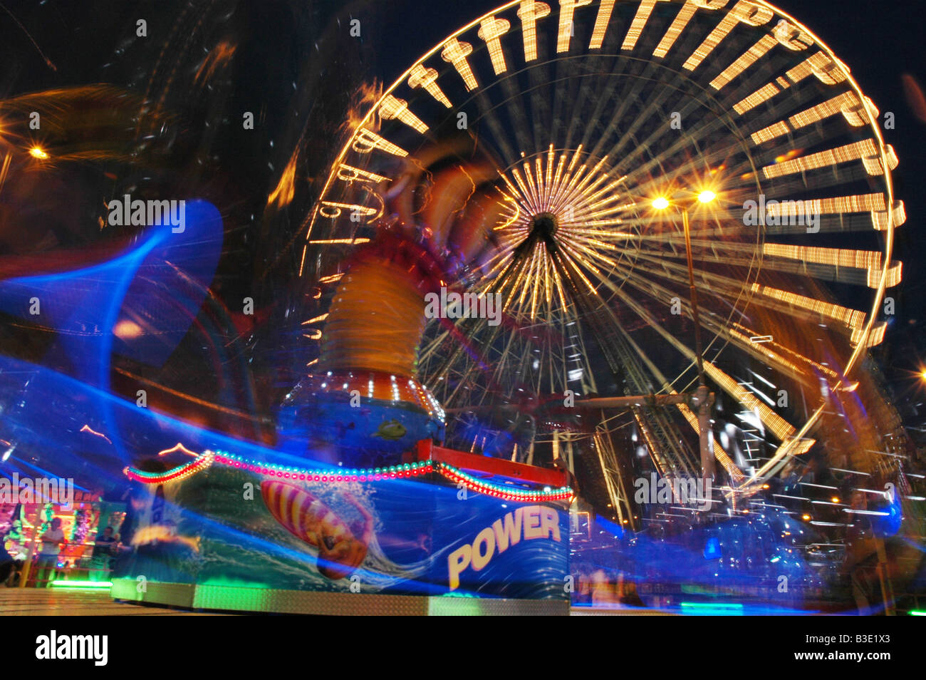 colourful fairground ride with ferris wheel at dusk Stock Photo - Alamy