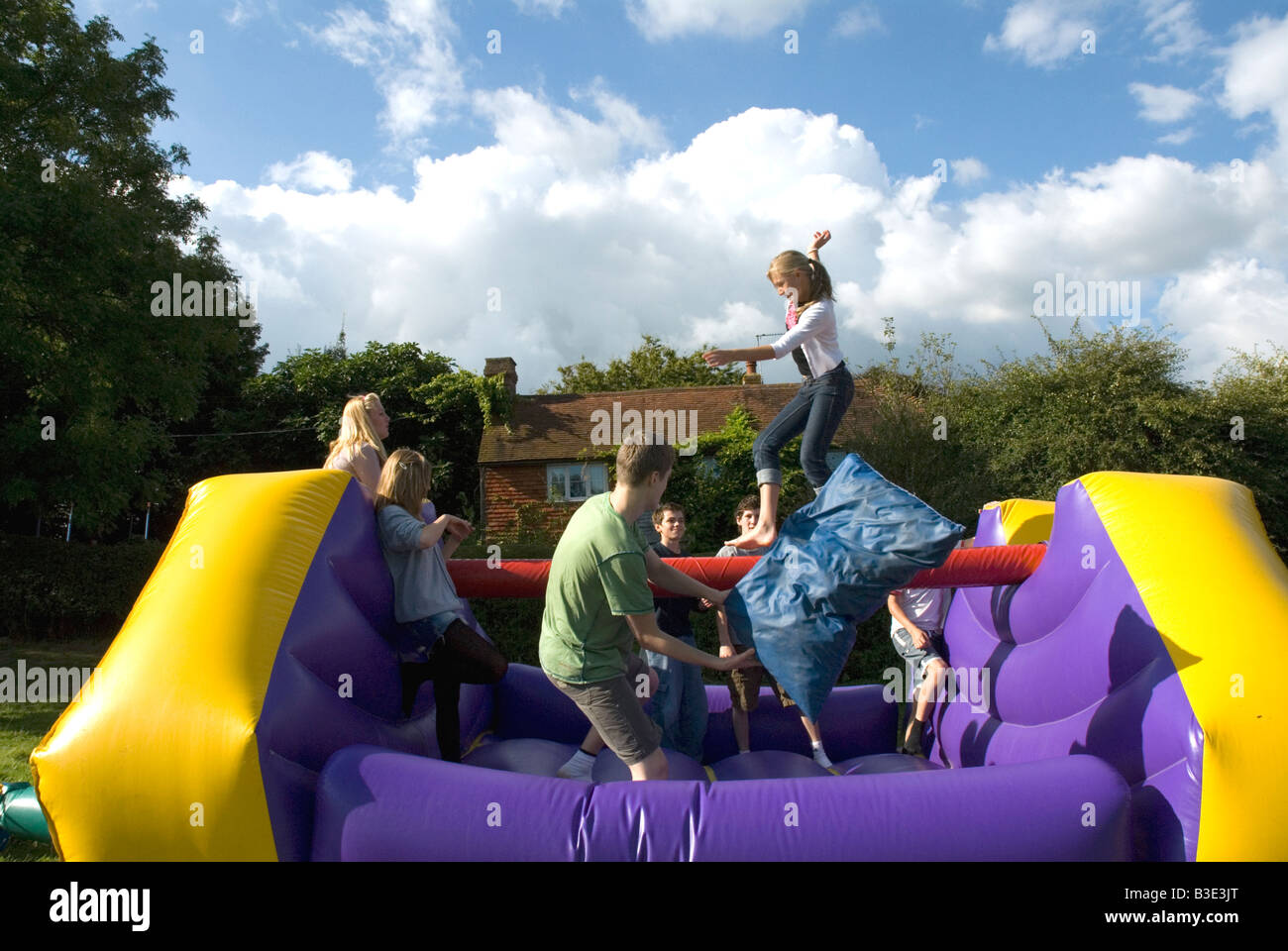 Teenagers playing on an inflatable bouncy castle outdoor birthday party ...