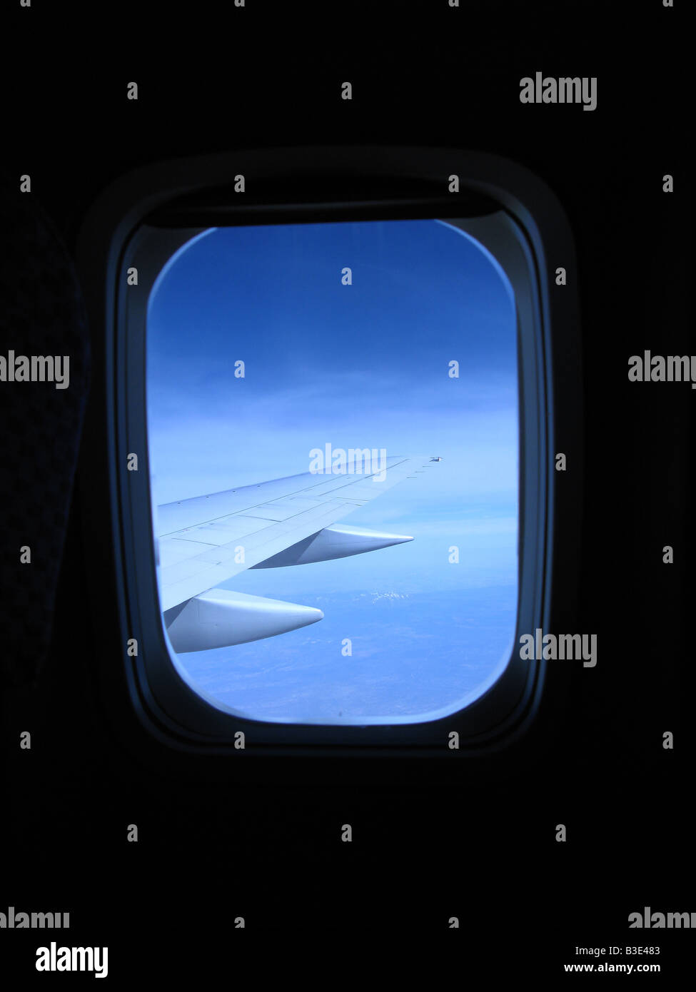 Looking out an airplane's cabin window with a view of the wing and blue ...