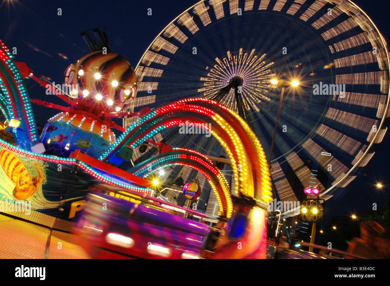 colourful fairground ride with ferris wheel at dusk Stock Photo - Alamy