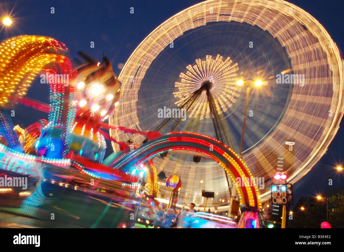 colourful fairground ride with ferris wheel at dusk Stock Photo - Alamy