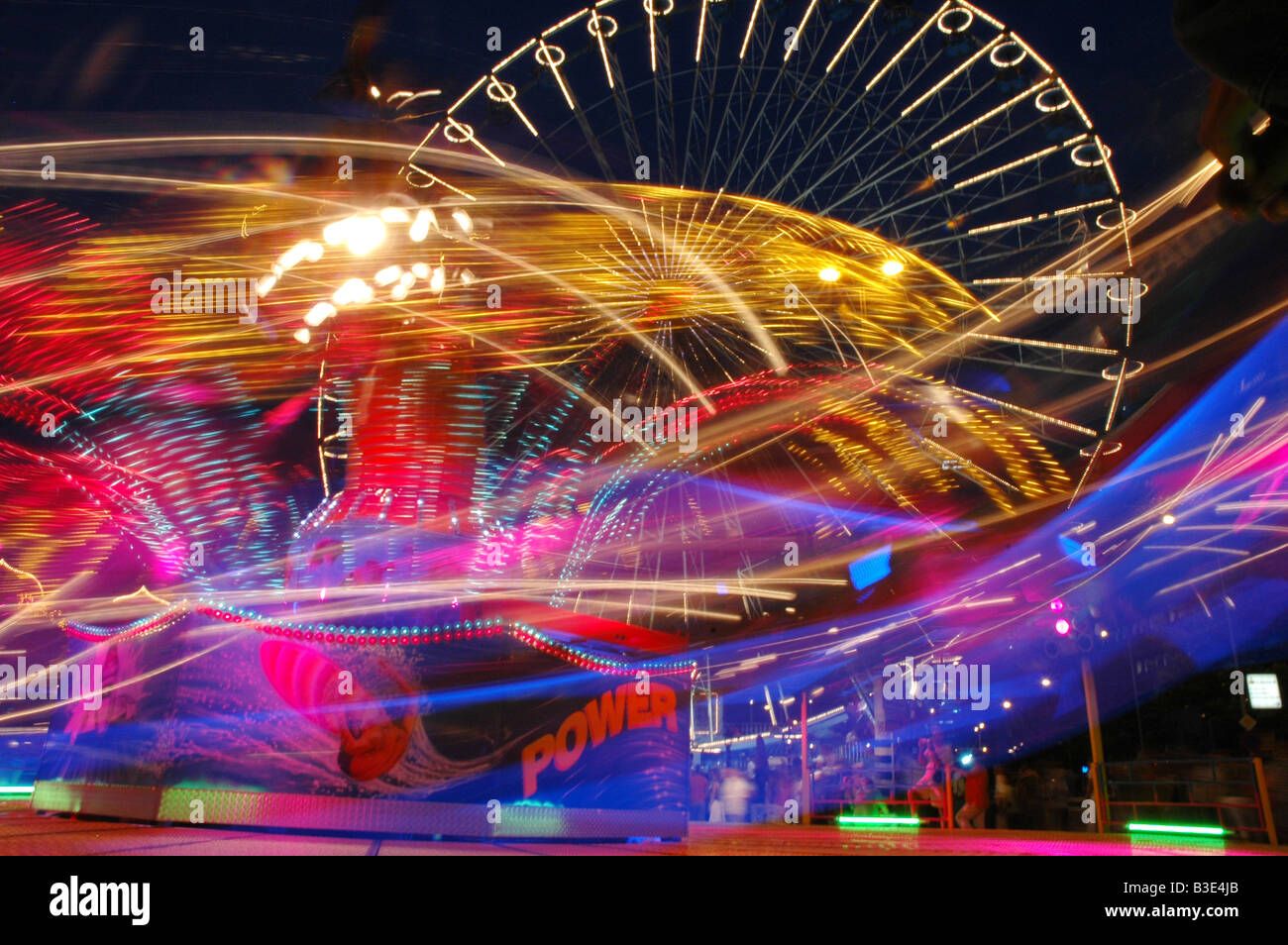 colourful fairground ride with ferris wheel at dusk Stock Photo - Alamy