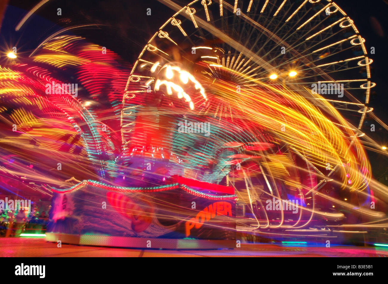colourful fairground ride with ferris wheel at dusk Stock Photo - Alamy