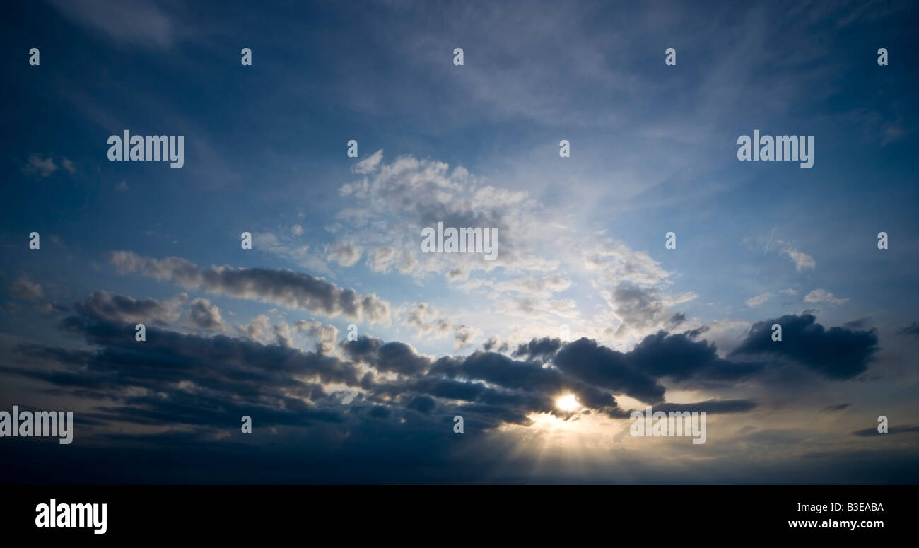 Sun hiding behind clouds showing rays of light Stock Photo - Alamy
