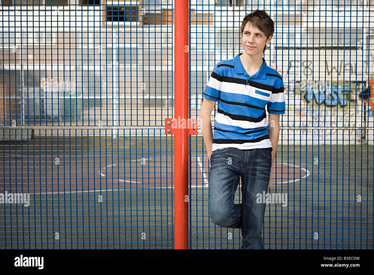 Teenage boy leaning on fence Stock Photo - Alamy