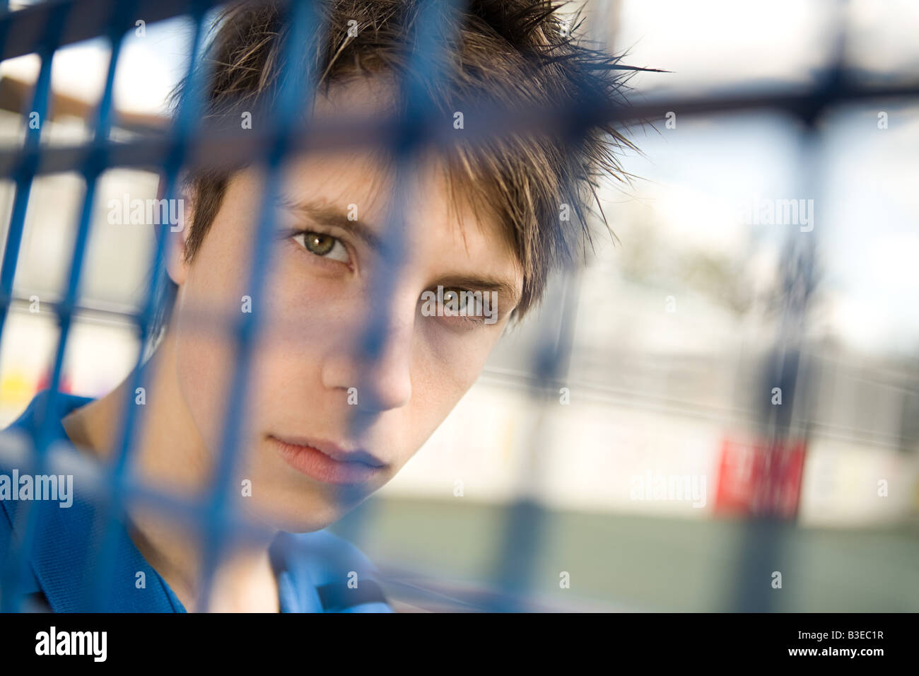 Teenage boy behind fence Stock Photo - Alamy