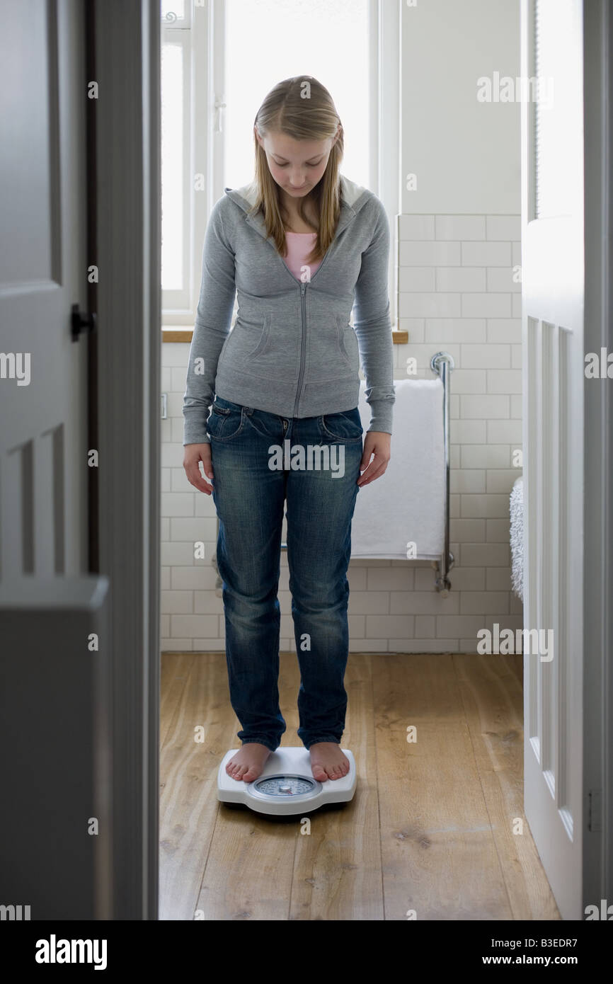 A teenage girl weighing herself Stock Photo - Alamy