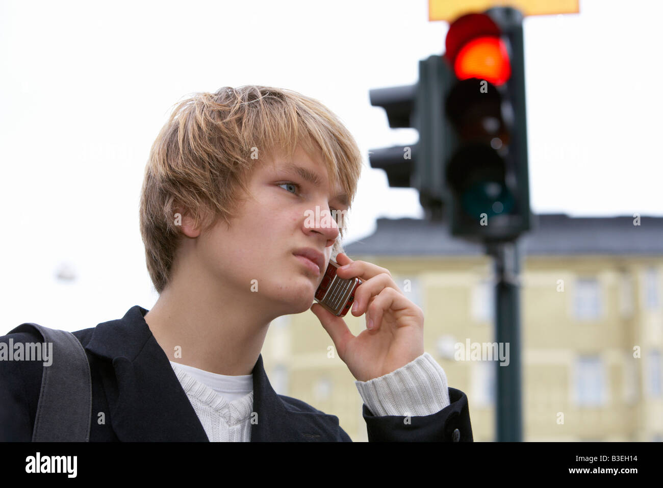 Teenage boy in street using mobile phone, red light in background Stock ...