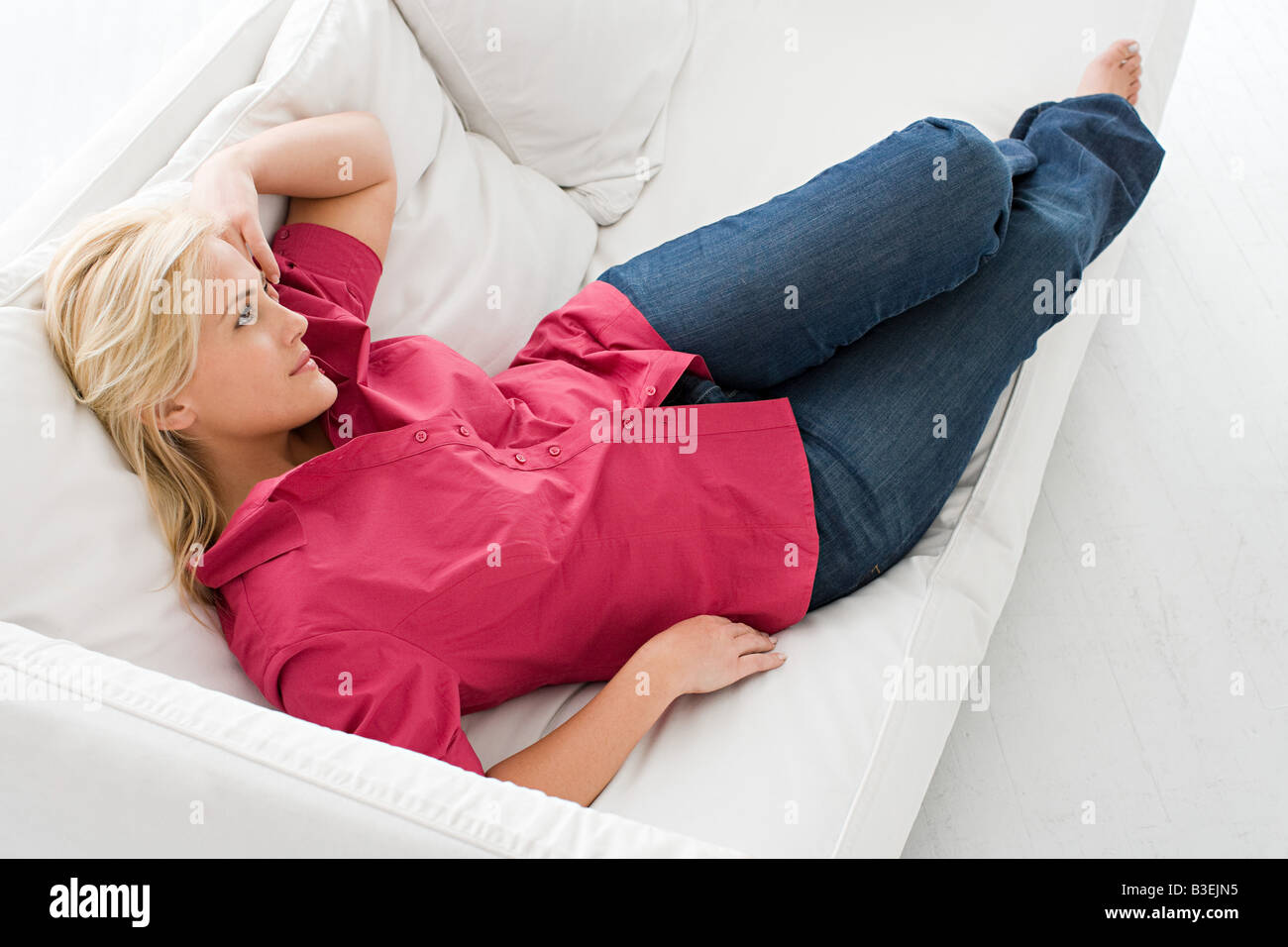 A young woman reclining on a sofa Stock Photo - Alamy