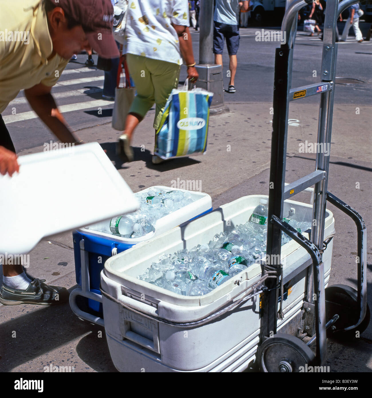A sidewalk vendor selling cold bottled drinking water from a chest of ...