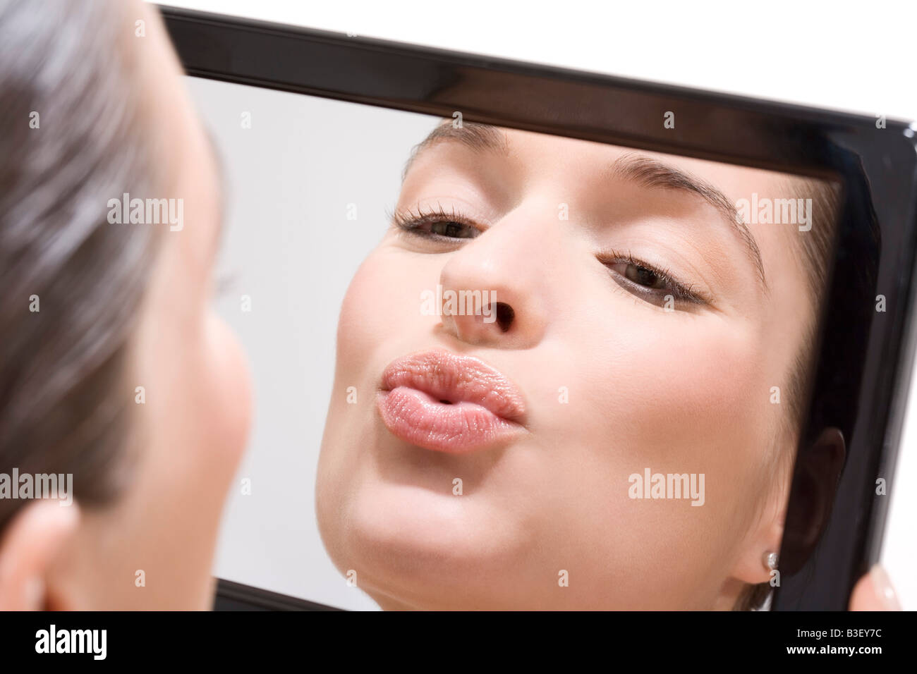 Young woman looking into mirror, pursing lips, portrait Stock Photo - Alamy