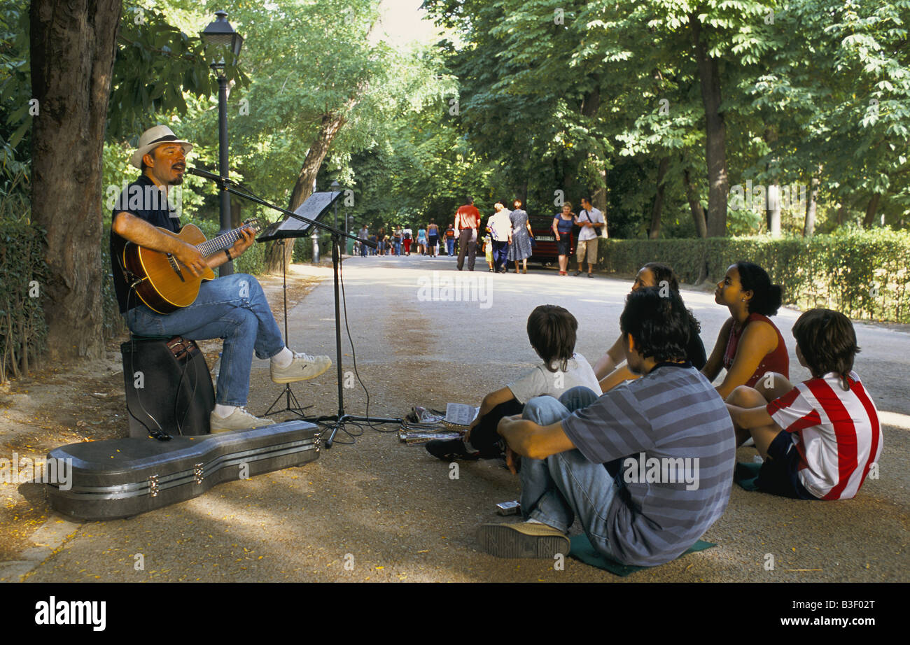 A busker entertains a group of young people in Parque del buen Retiro ...