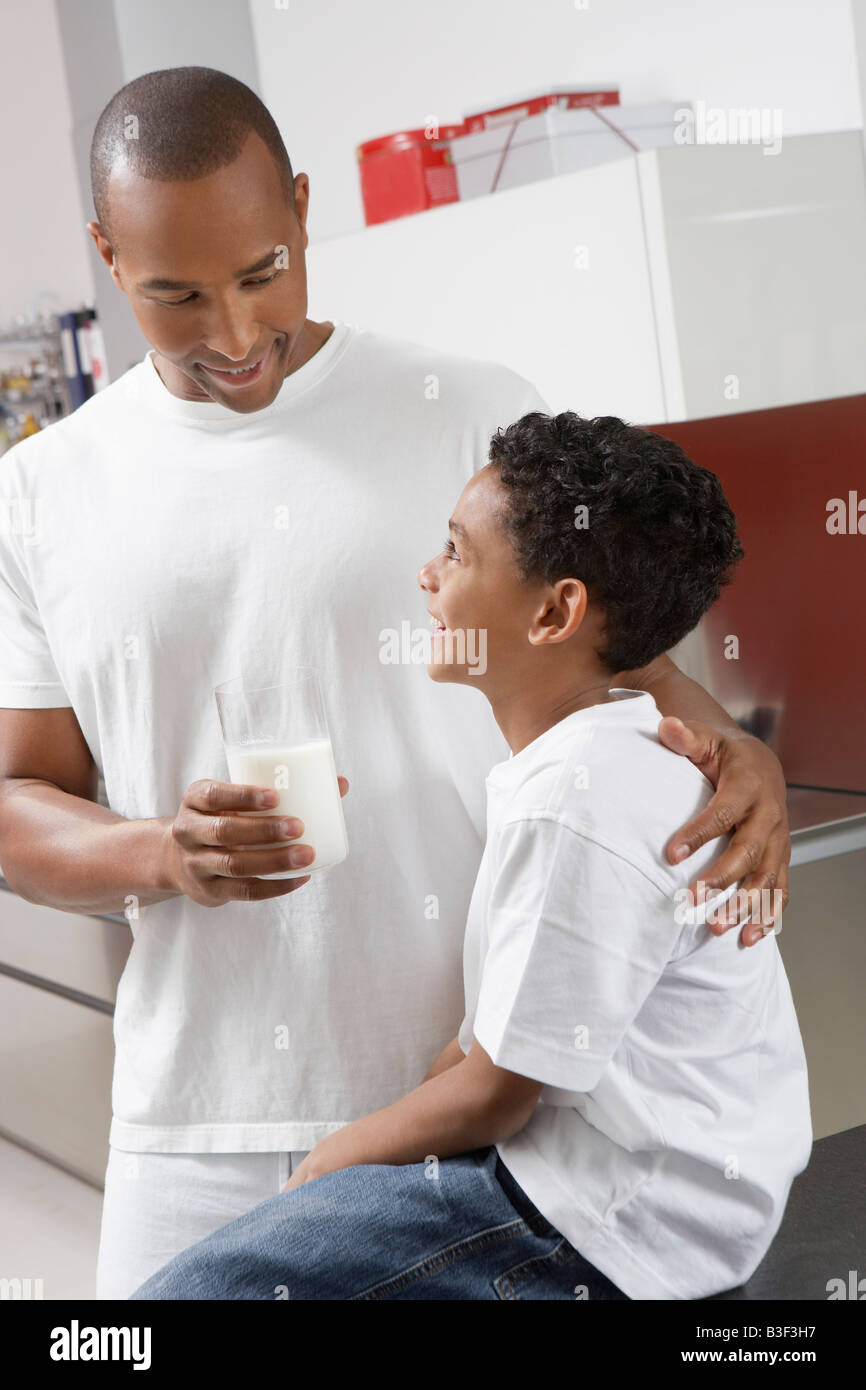 Father holding glass of milk, embracing son (7-9) indoors Stock Photo ...