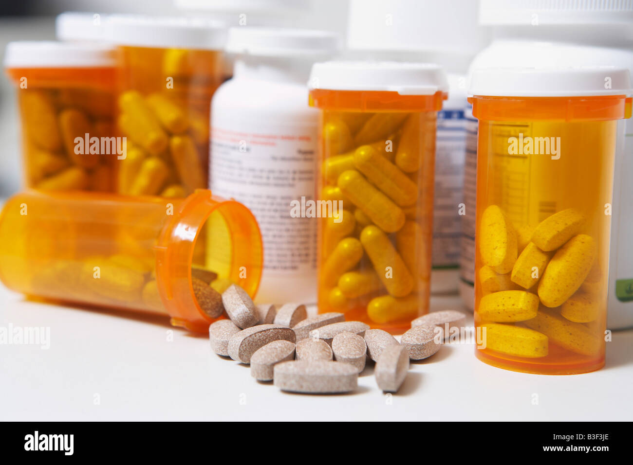 Bottles of pills, one spilling, close-up Stock Photo - Alamy