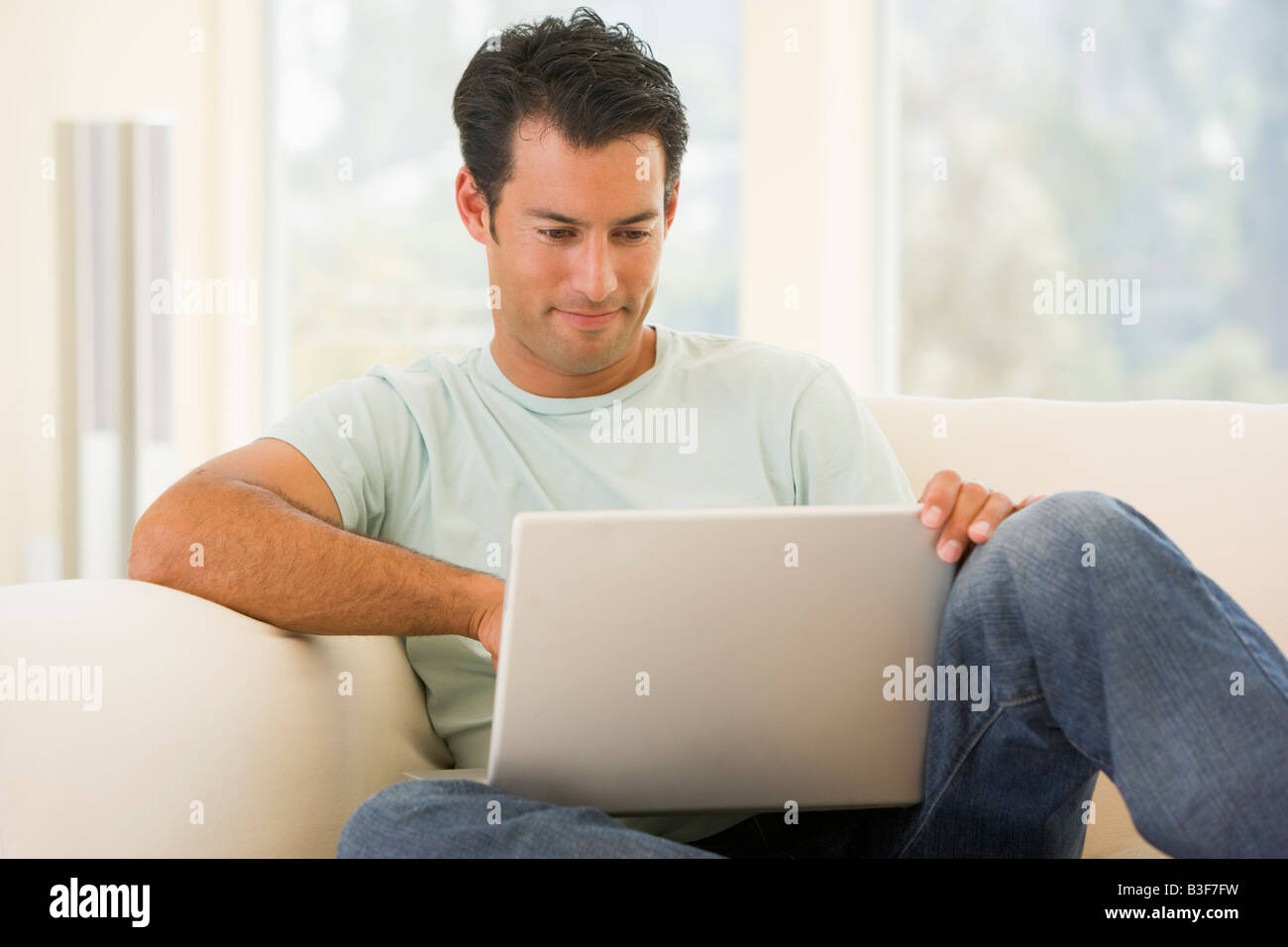 Man in living room using laptop Stock Photo - Alamy
