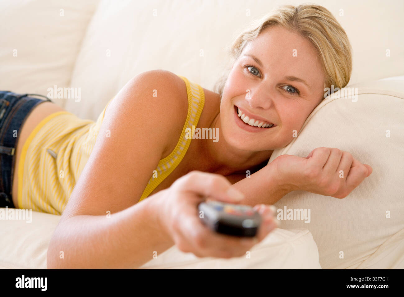 Woman in living room holding remote control smiling Stock Photo - Alamy