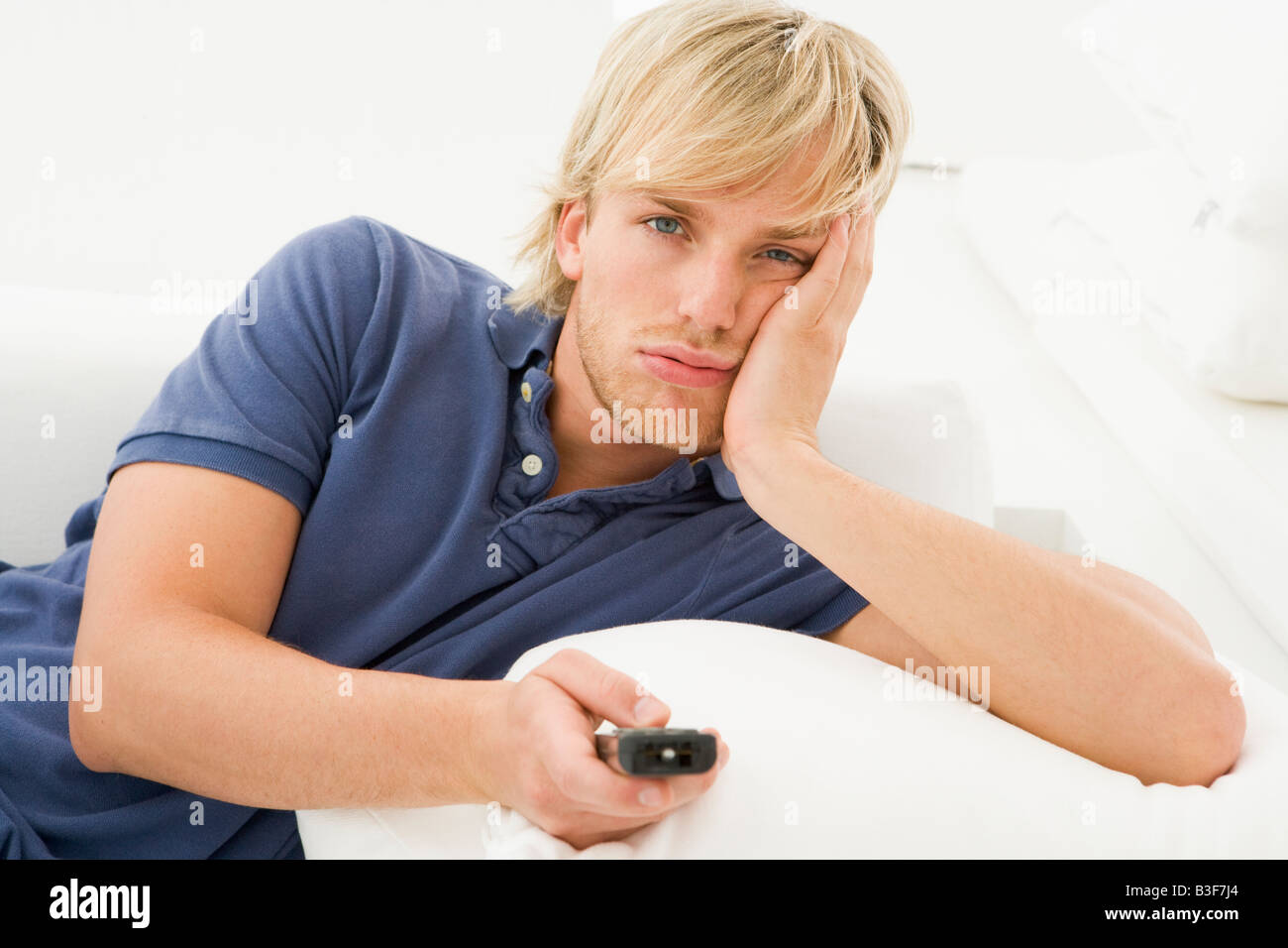 Man in living room holding remote control Stock Photo - Alamy