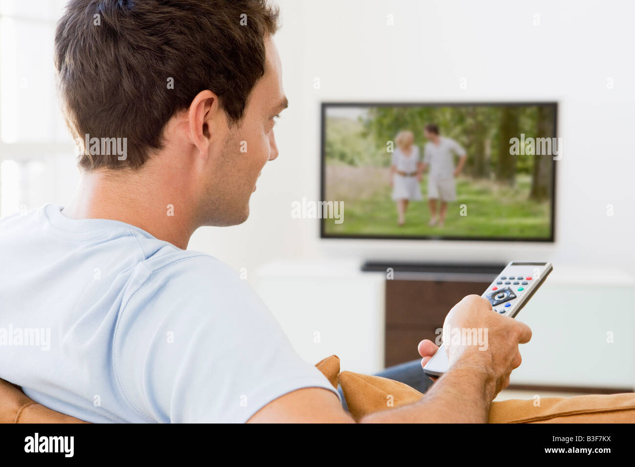 Man in living room watching television Stock Photo - Alamy