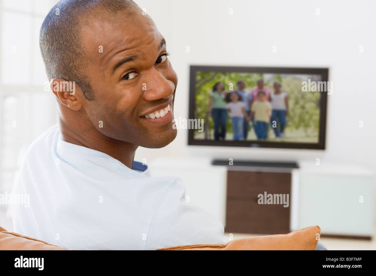 Man in living room watching television smiling Stock Photo - Alamy