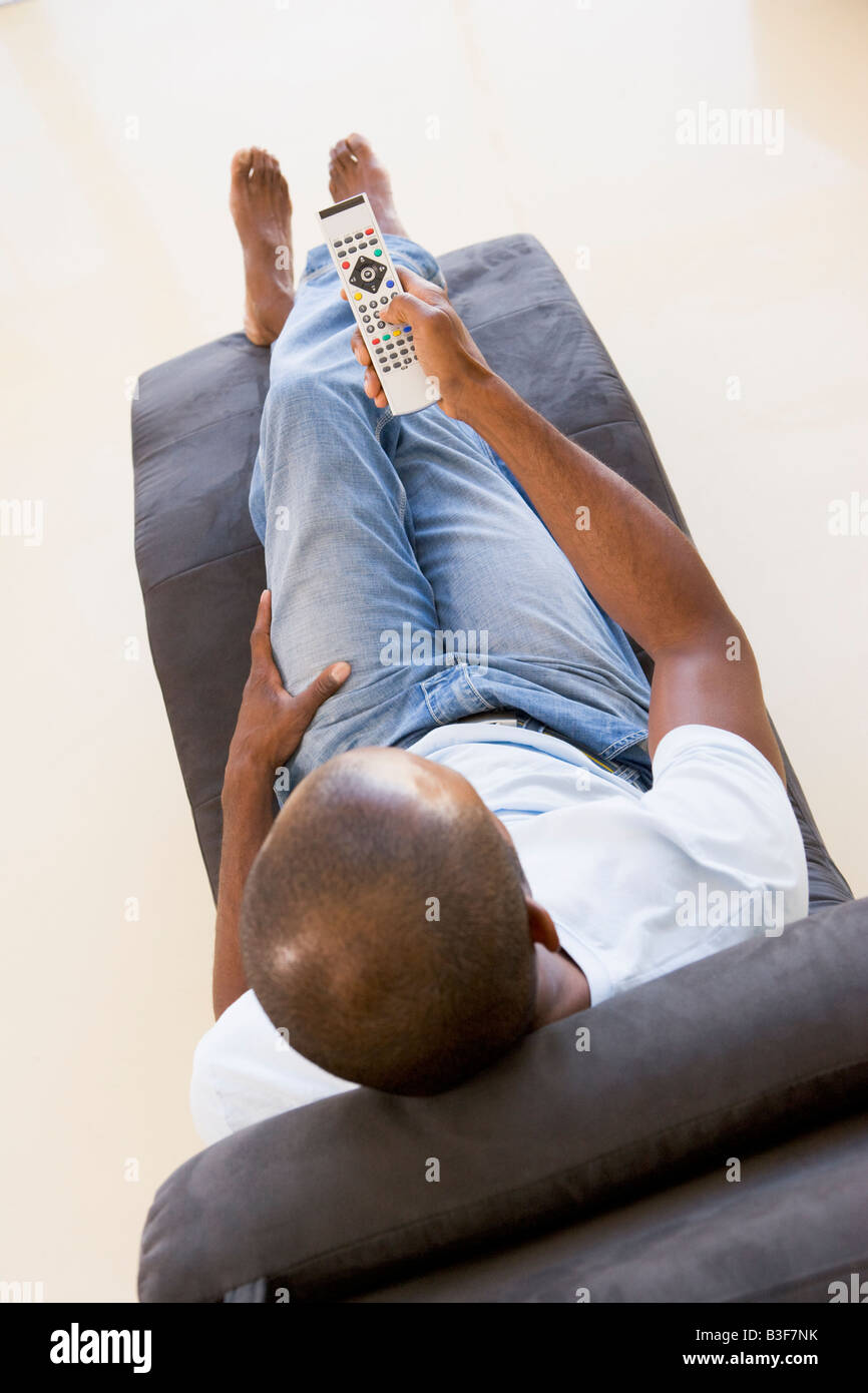 Man sitting in chair using remote control Stock Photo - Alamy
