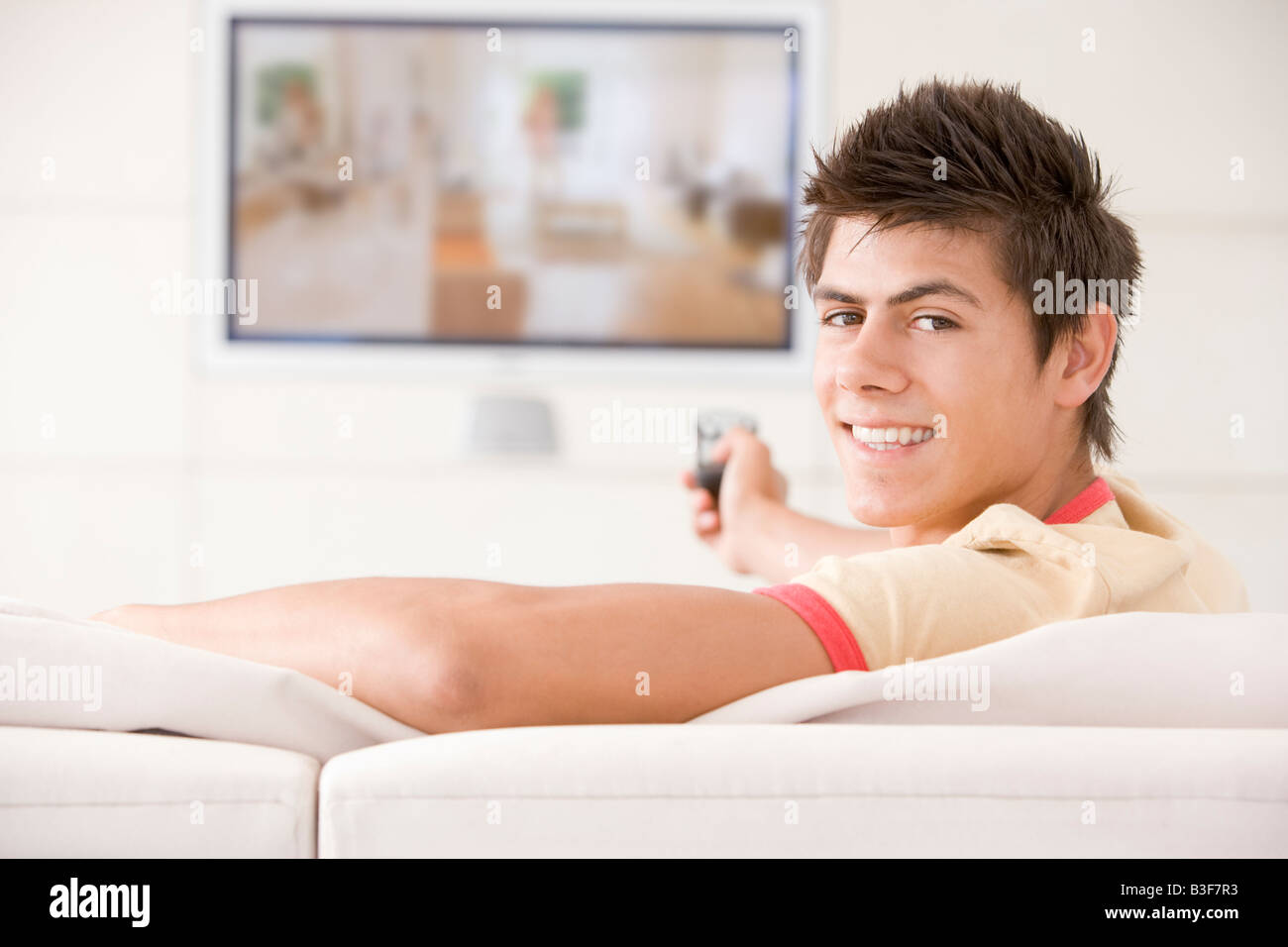 Man in living room watching television smiling Stock Photo - Alamy