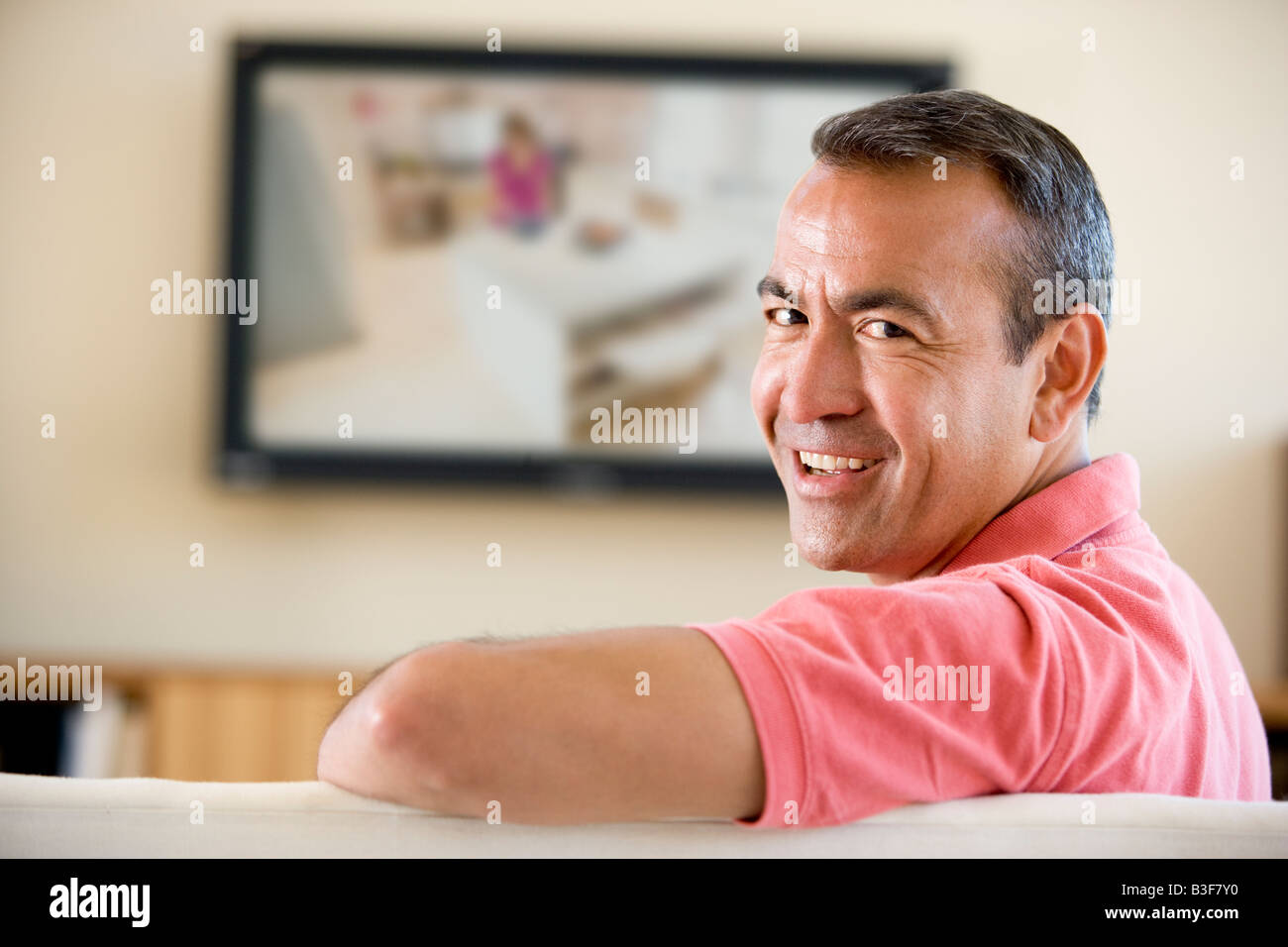 Man in living room watching television smiling Stock Photo - Alamy