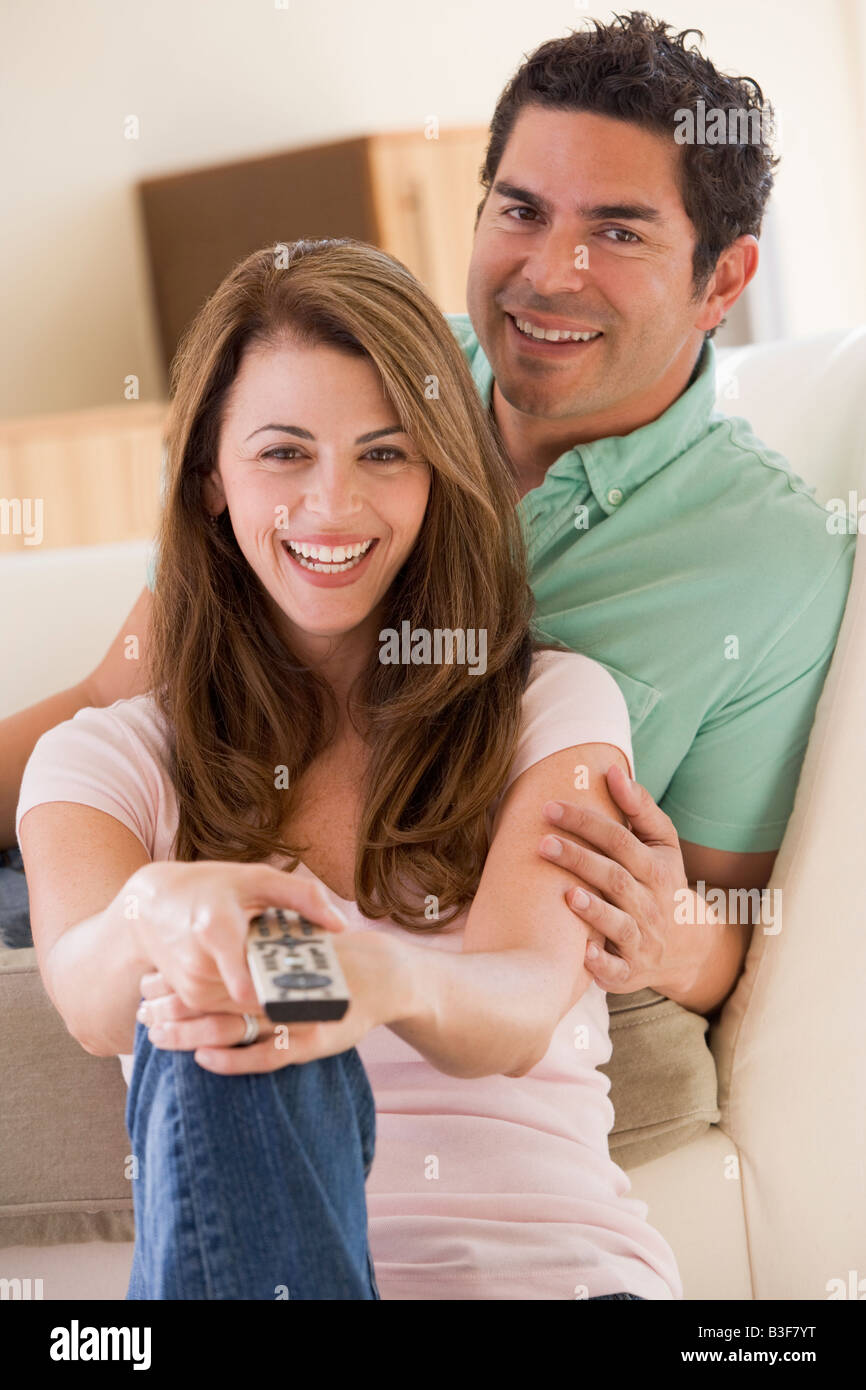 Couple in living room with remote control smiling Stock Photo - Alamy