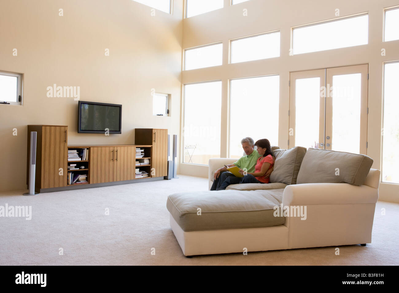 Couple reading book in living room Stock Photo - Alamy