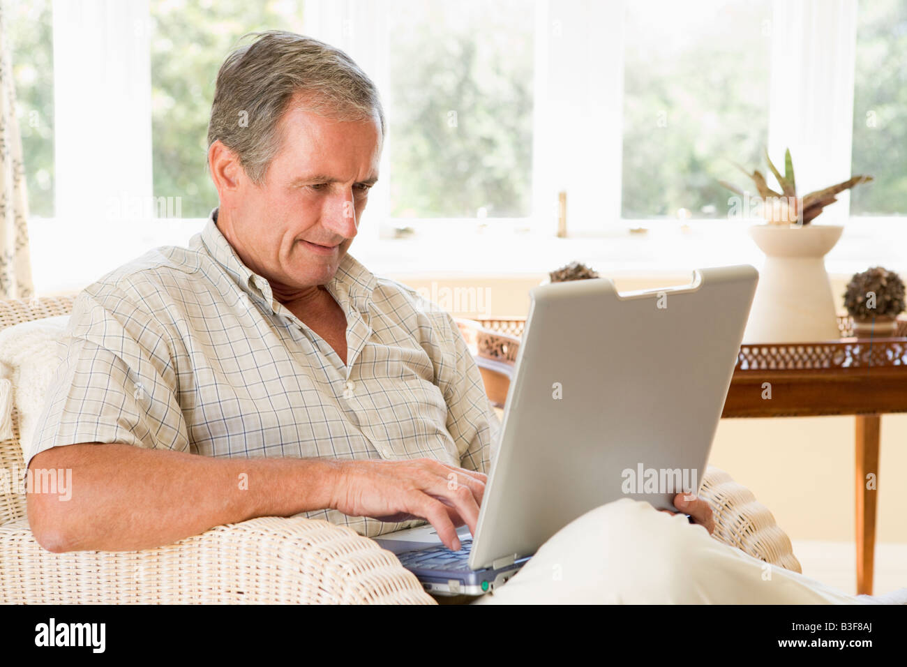 Man in living room with laptop Stock Photo - Alamy