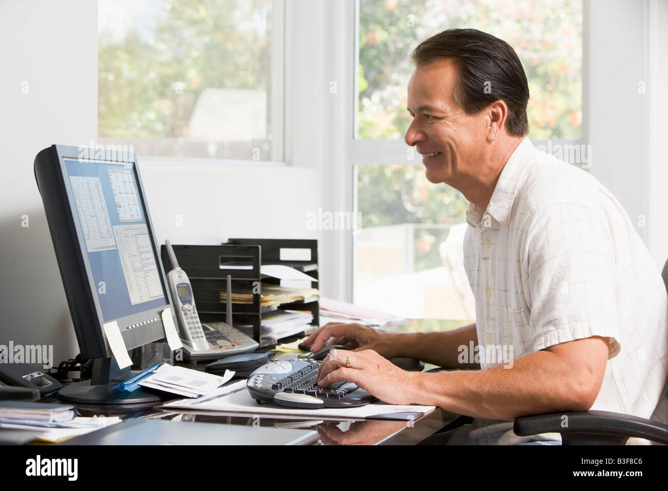 Man in home office at computer smiling Stock Photo - Alamy