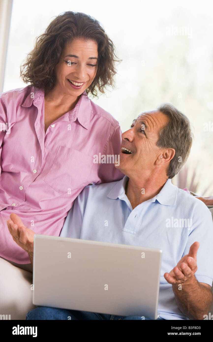 Couple in living room with laptop smiling Stock Photo - Alamy