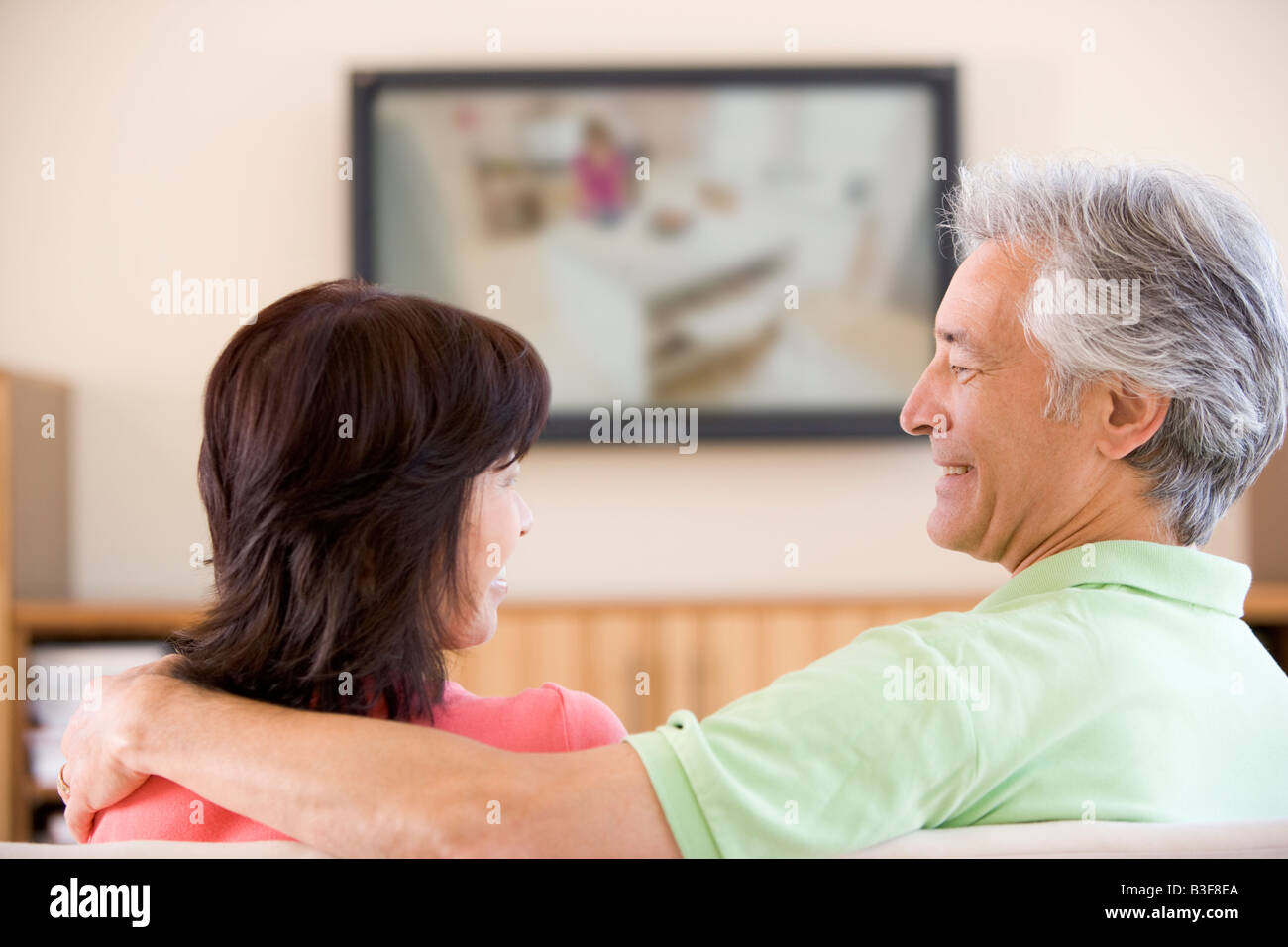 Couple watching television smiling Stock Photo - Alamy